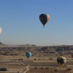 Multiple hot air balloons flying over Cappadocia at sunrise