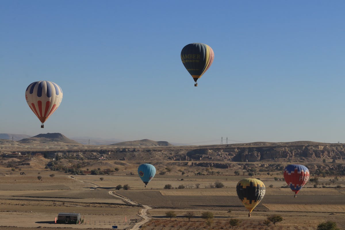 Multiple hot air balloons flying over Cappadocia at sunrise