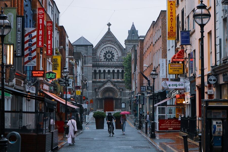 Street view in Dublin with St Ann's Church and shops, people walking in the rain