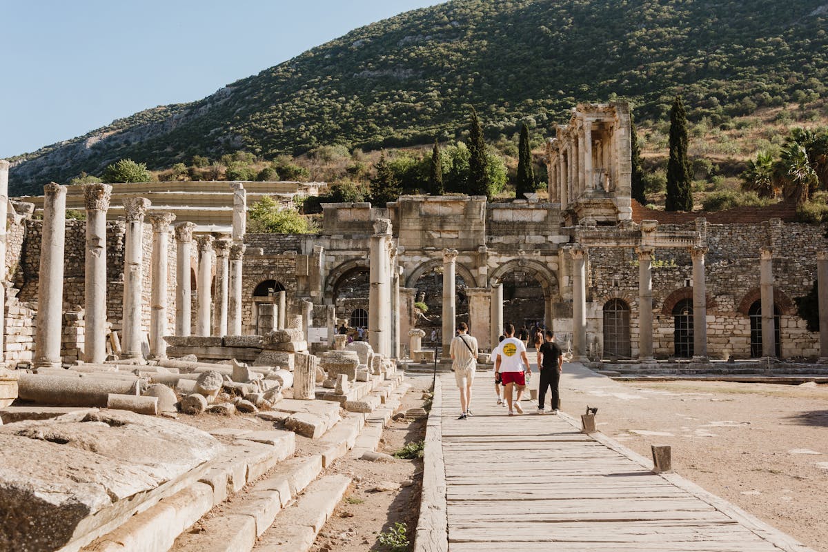 Tourists walking through the ancient ruins of Ephesus with mountain backdrop