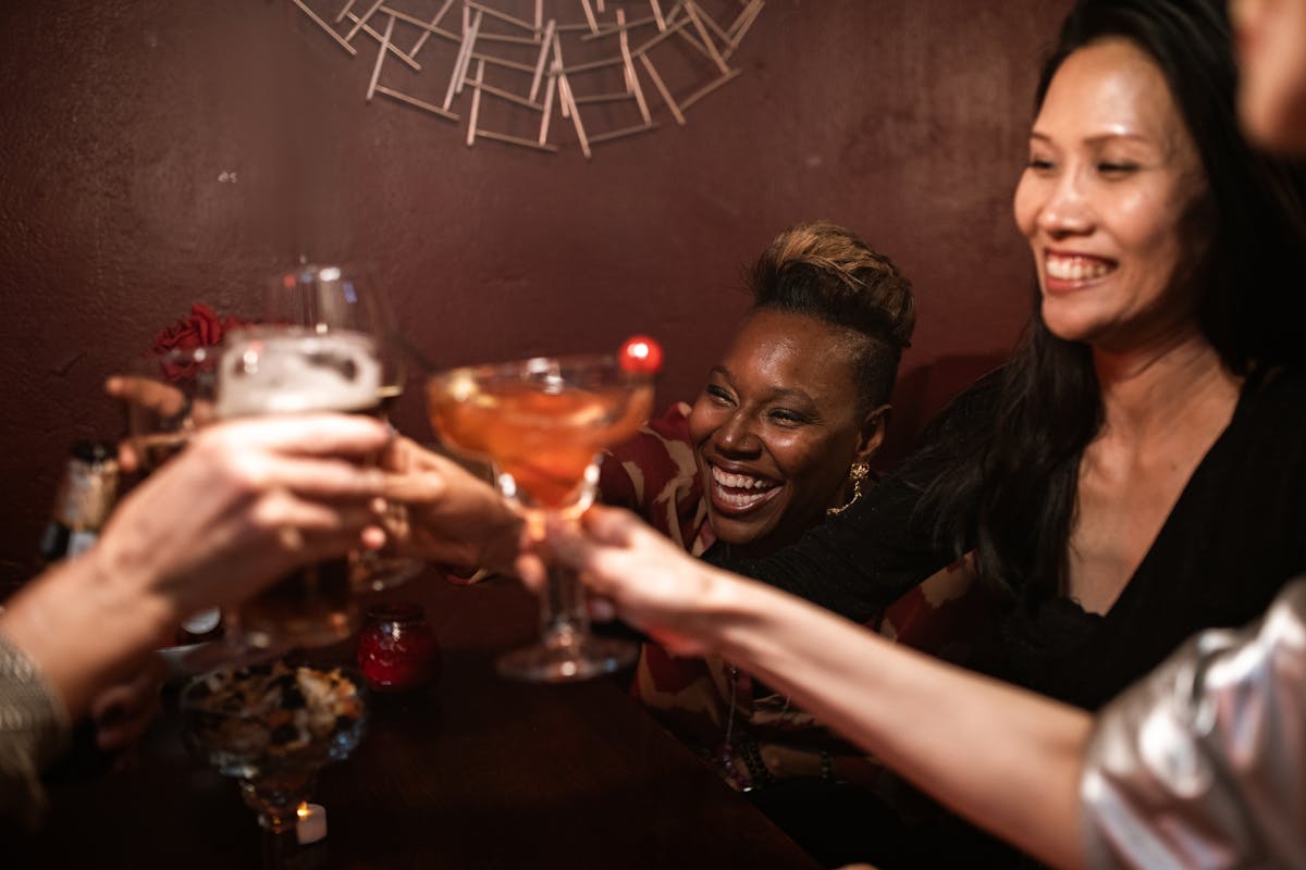 Group of friends toasting drinks in a cozy bar setting