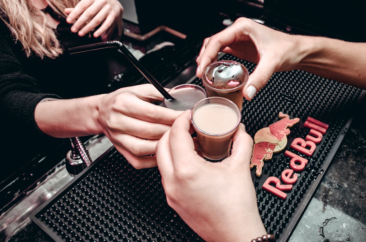 Hands toasting shot glasses on bar counter