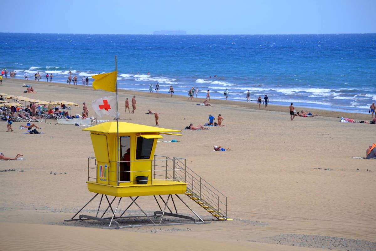 Summer scene on Maspalomas Beach Gran Canaria with yellow lifeguard tower and beachgoers