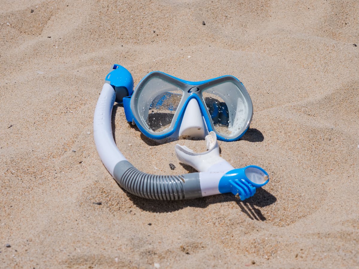 Blue snorkel mask set on a sandy beach