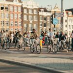People cycling through Amsterdam on a sunny day with classic Dutch architecture