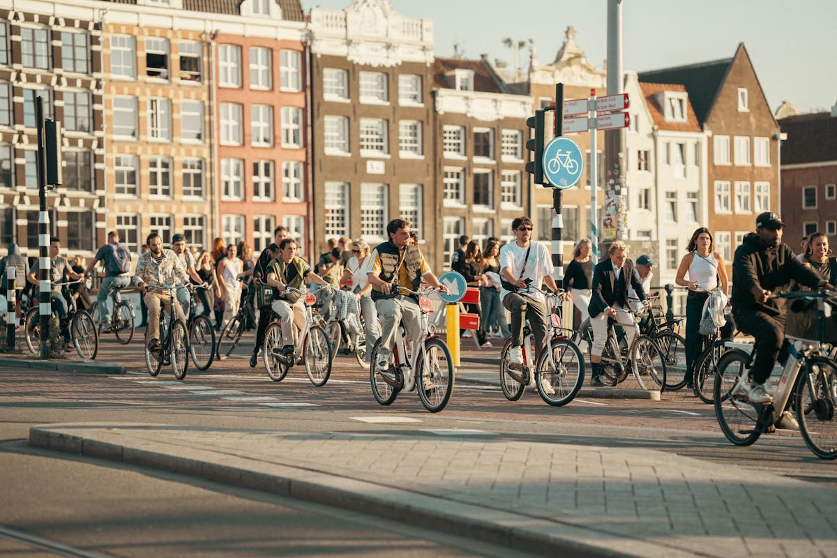 People cycling through Amsterdam on a sunny day with classic Dutch architecture