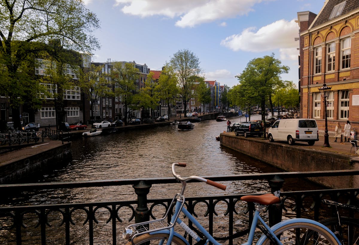 Blue bicycle on Amsterdam canal bridge with boats and historic buildings
