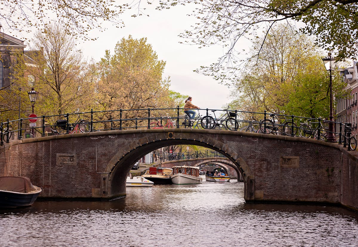 A cyclist crosses a historic bridge over Amsterdam canals