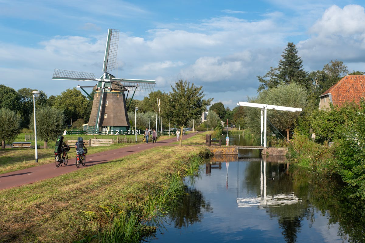 Cyclists on a sunny bicycle path near a windmill in the Netherlands