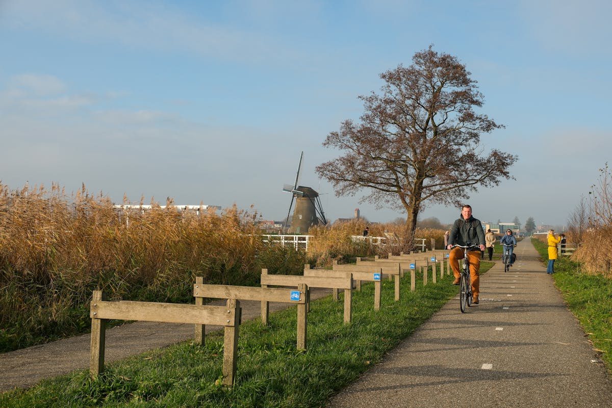 Man riding a bicycle on a path with a windmill in the background