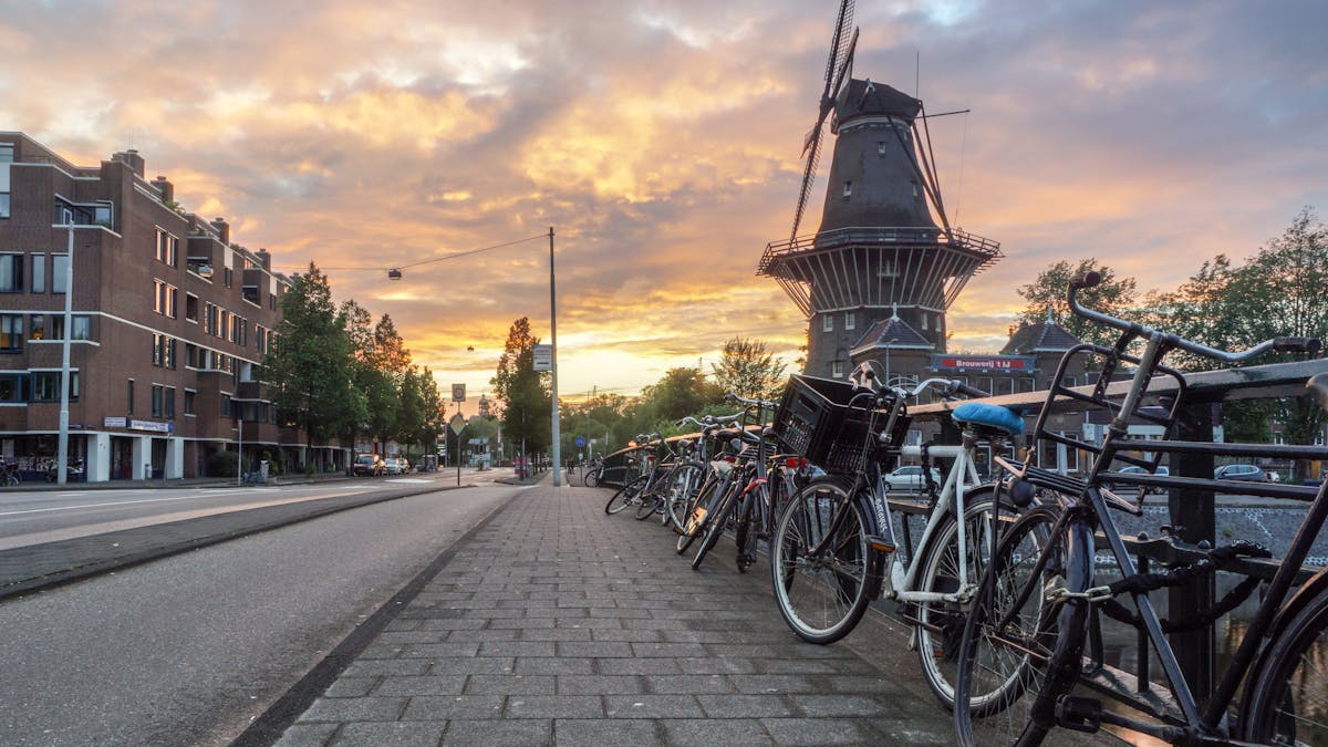 Rows of bicycles on a street in Amsterdam with a windmill in the background