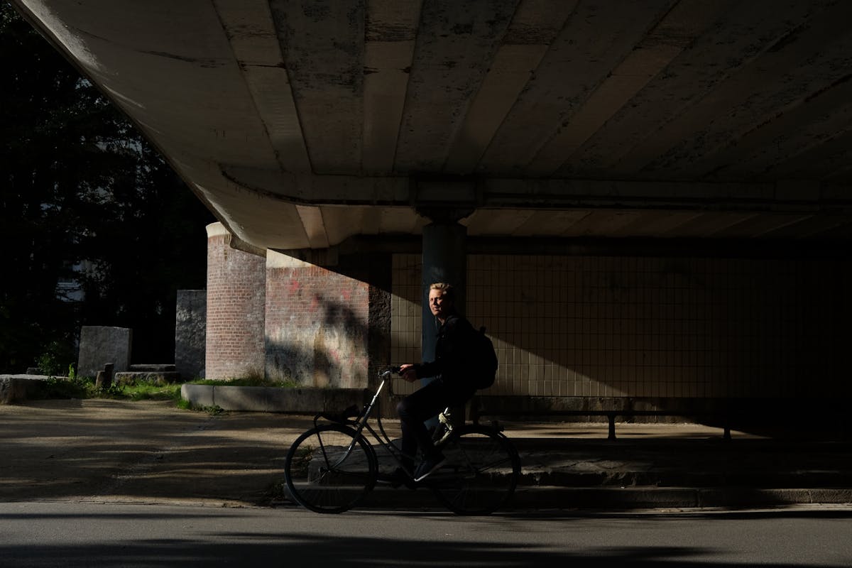 A man cycling under a bridge in Amsterdam