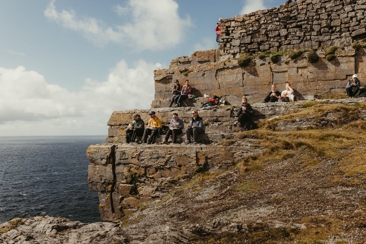 Tourists on the Aran Islands cliffs enjoying scenic views over the Atlantic