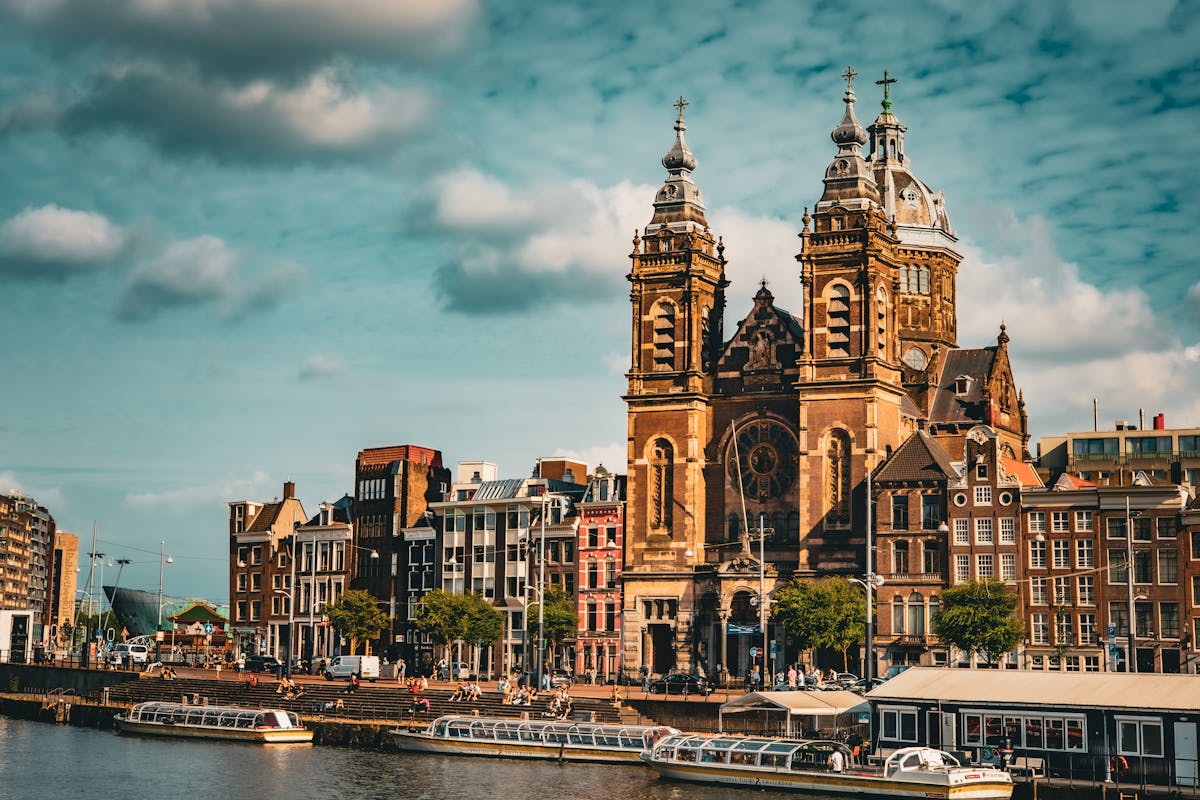 Scenic view of Amsterdam Basilica of St Nicholas with canal boats under a cloudy sky