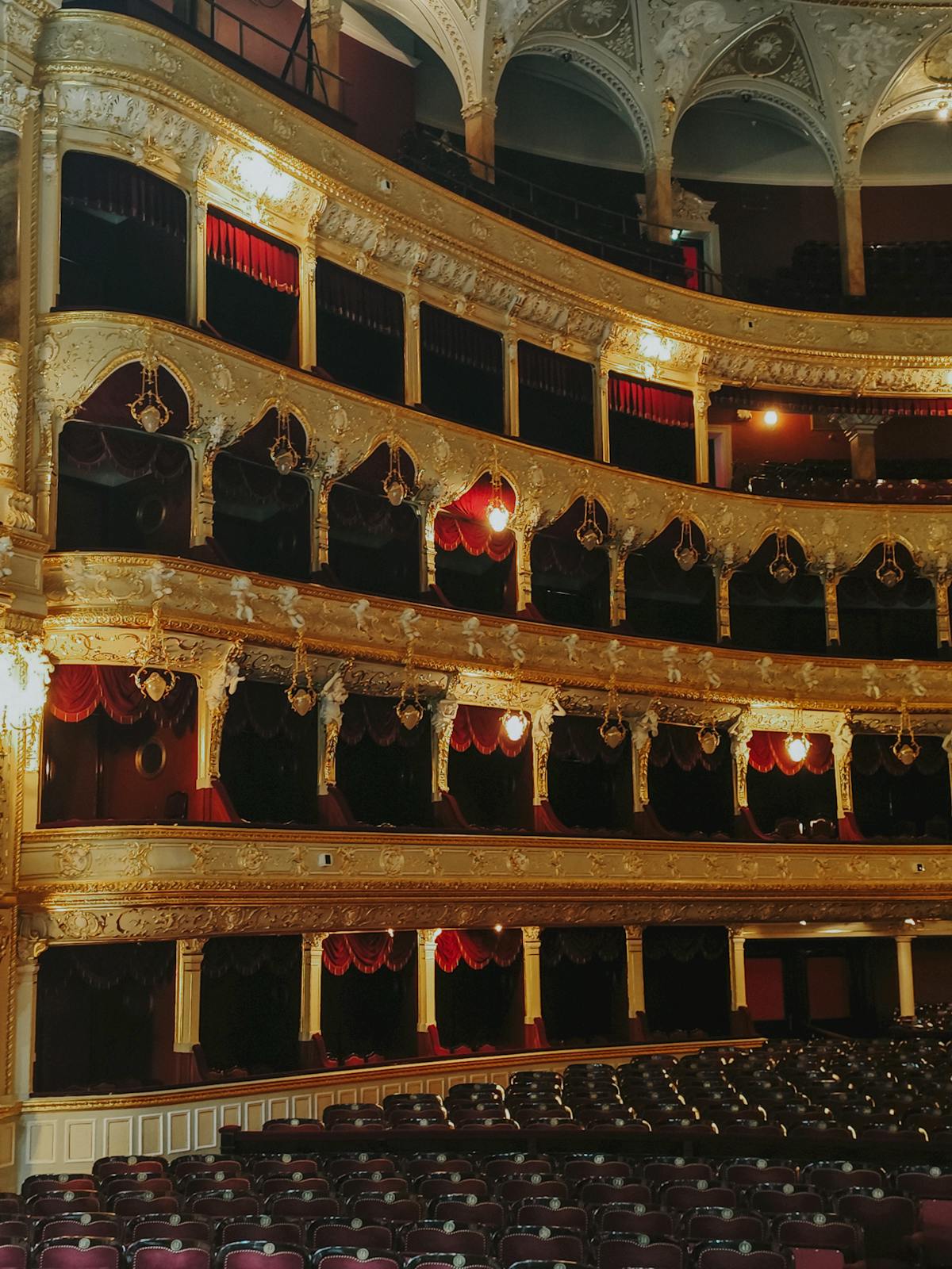 Luxurious theatre interior with ornate gold designs and red velvet balconies