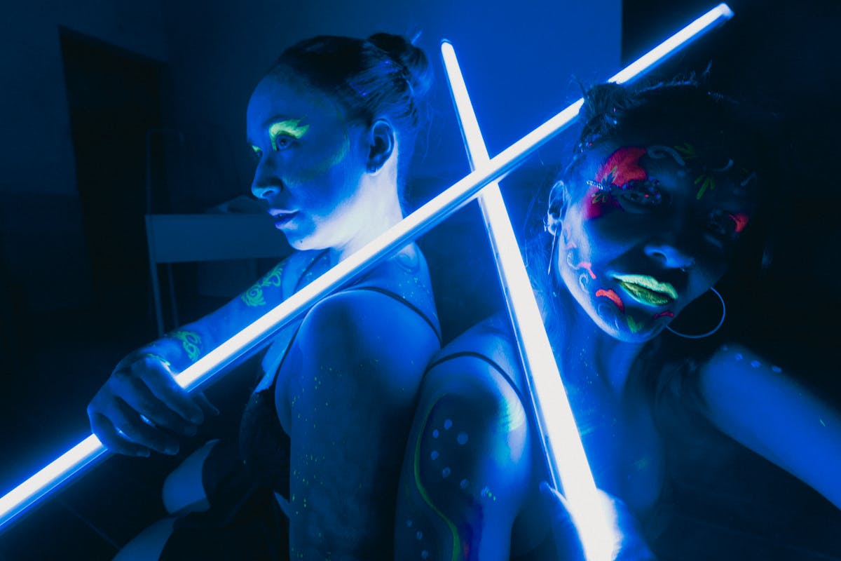 Women illuminated by neon colors and UV light in a performance setting