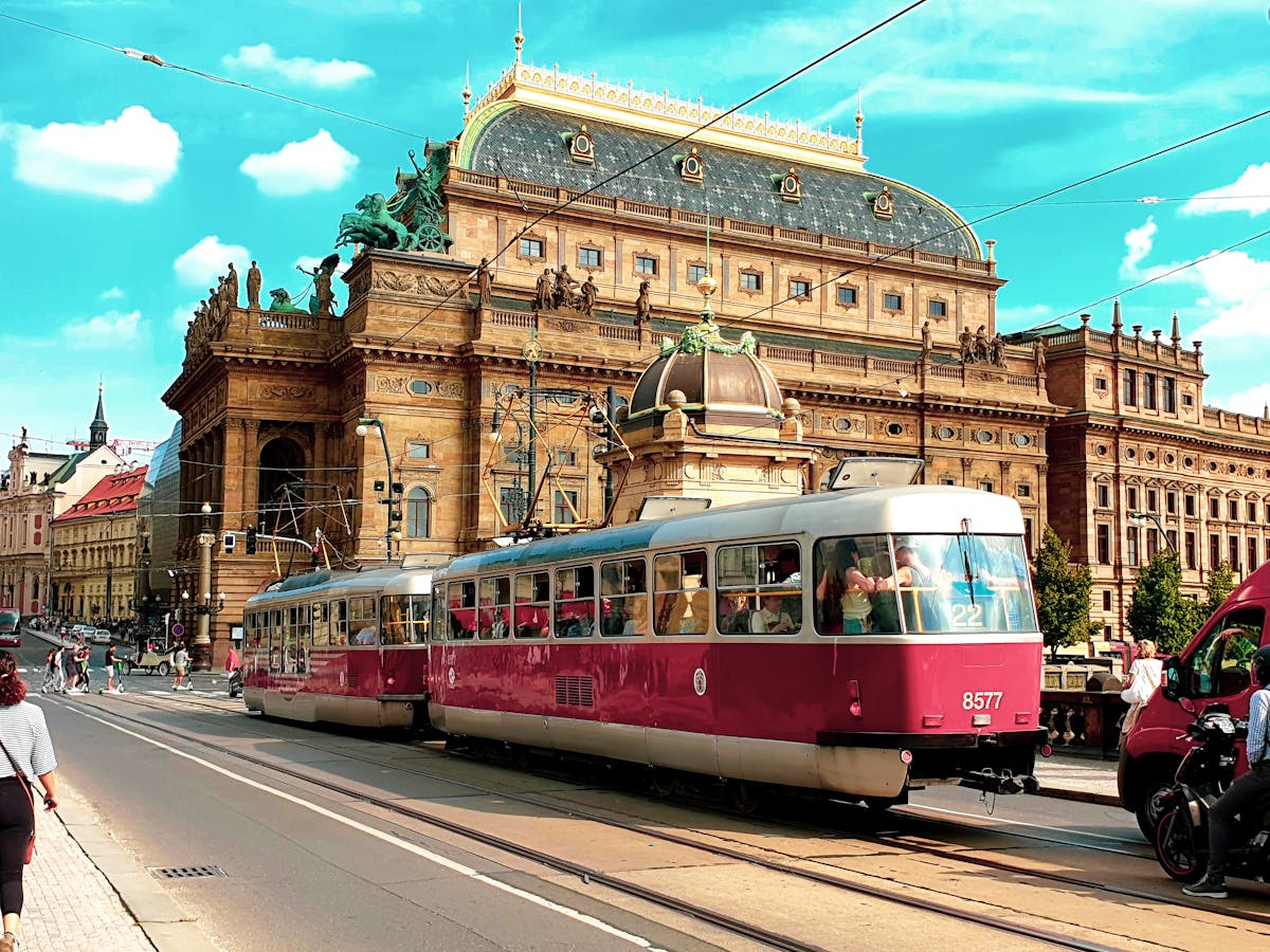 A red tram passes by the National Theatre in Prague