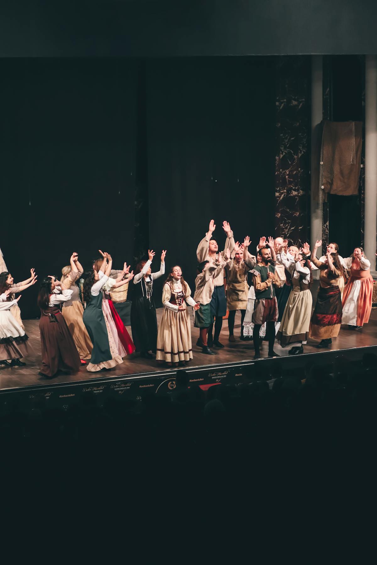Group of actors performing a theatrical play on stage with expressive gestures