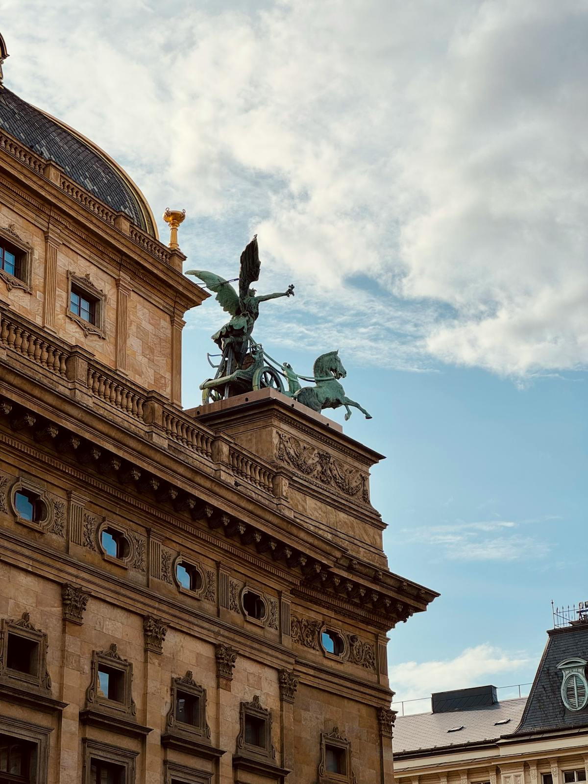 Elegant Prague building with symbolic rooftop sculptures under a blue sky