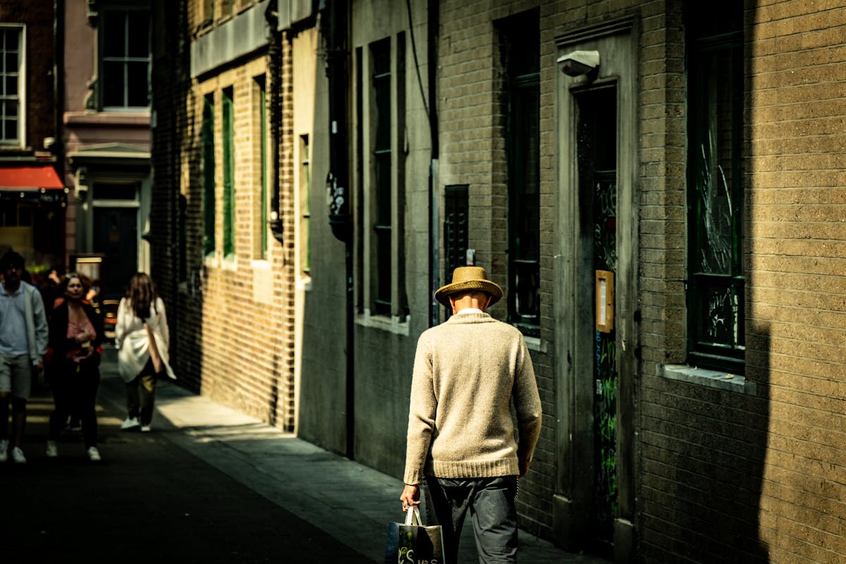 Man in hat walking down a sunlit Dublin alleyway