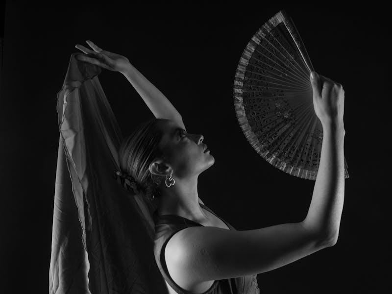 Monochrome photo of a flamenco dancer holding a fan in a dramatic pose