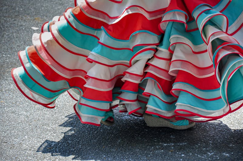 Close-up detail of a colorful ruffled flamenco skirt in red, teal, and white