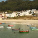 Colorful fishing boats and a green coastal village in Galicia Spain