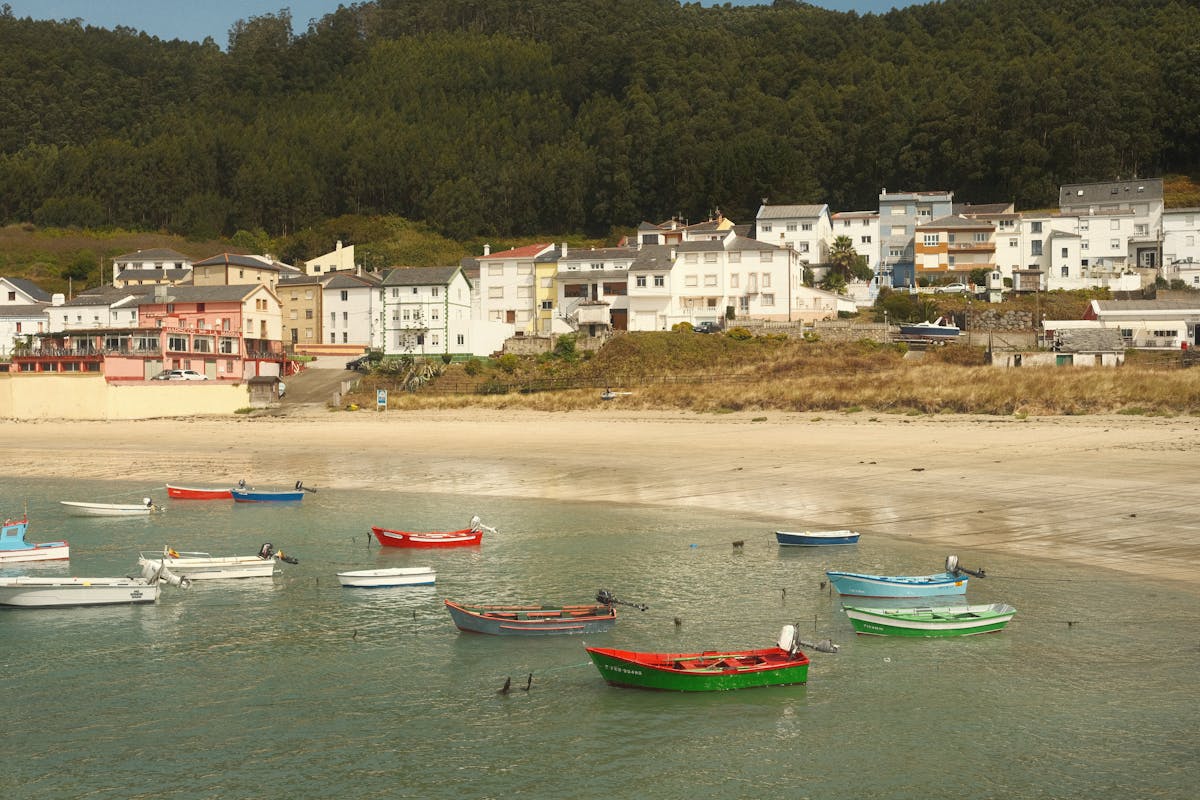 Colorful fishing boats and a green coastal village in Galicia Spain