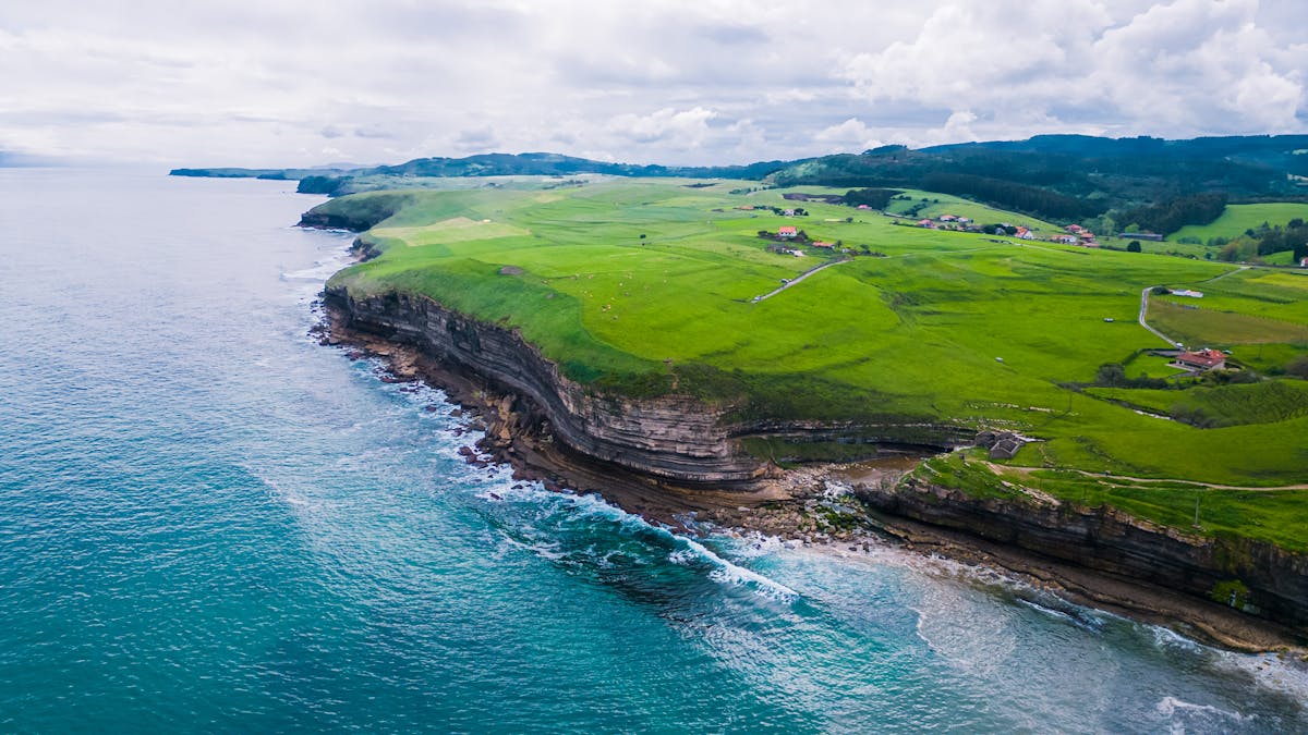 Aerial view of the lush green coastline and cliffs of Galicia meeting the Atlantic Ocean