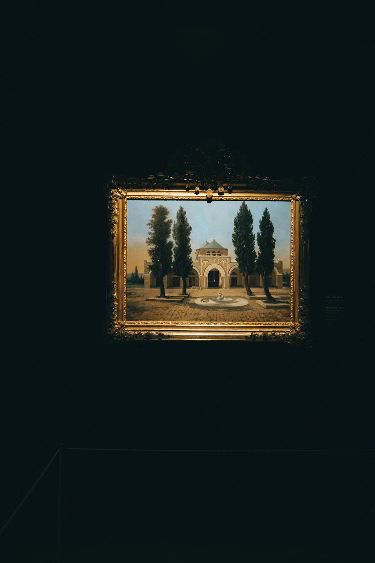 A framed painting displayed in a dimly lit museum gallery setting