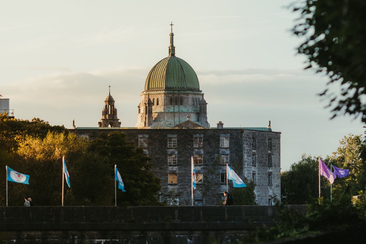 Galway Cathedral dome with flags and greenery at sunset
