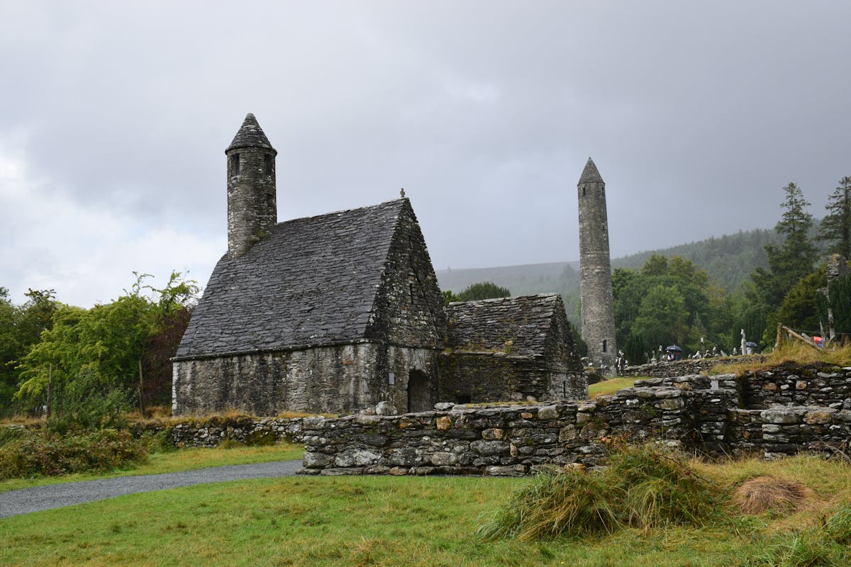 Ancient stone church of St Kevin at Glendalough with round tower in the background