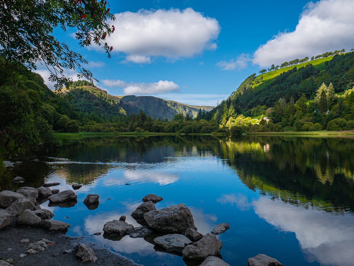Scenic view of calm Glendalough Lake with green hills and clear skies