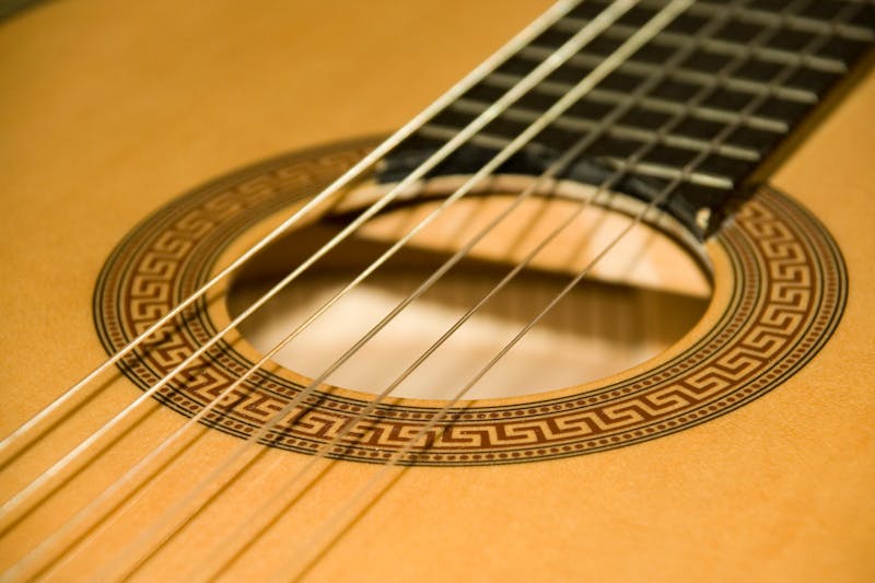 Detailed close-up of classical acoustic guitar strings and ornate soundhole