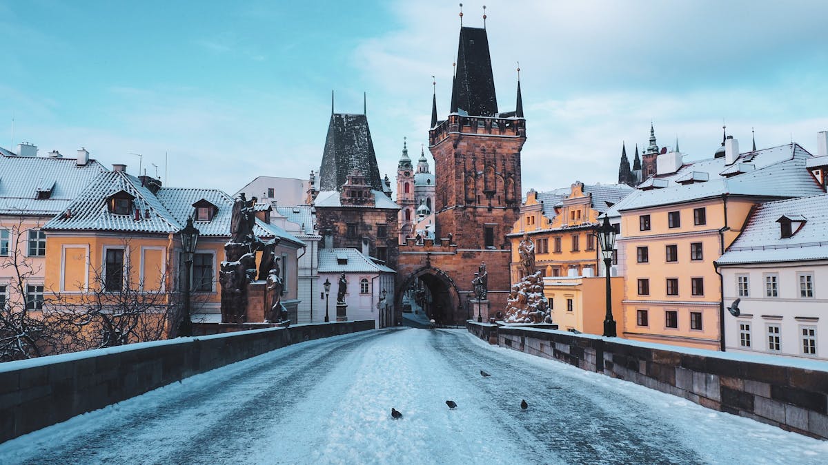 Snow-covered Charles Bridge leading to gothic towers in Prague