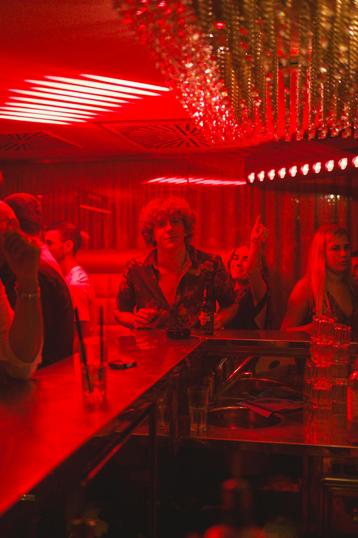 Lively group enjoying a night out at a bar with red lighting and chandeliers