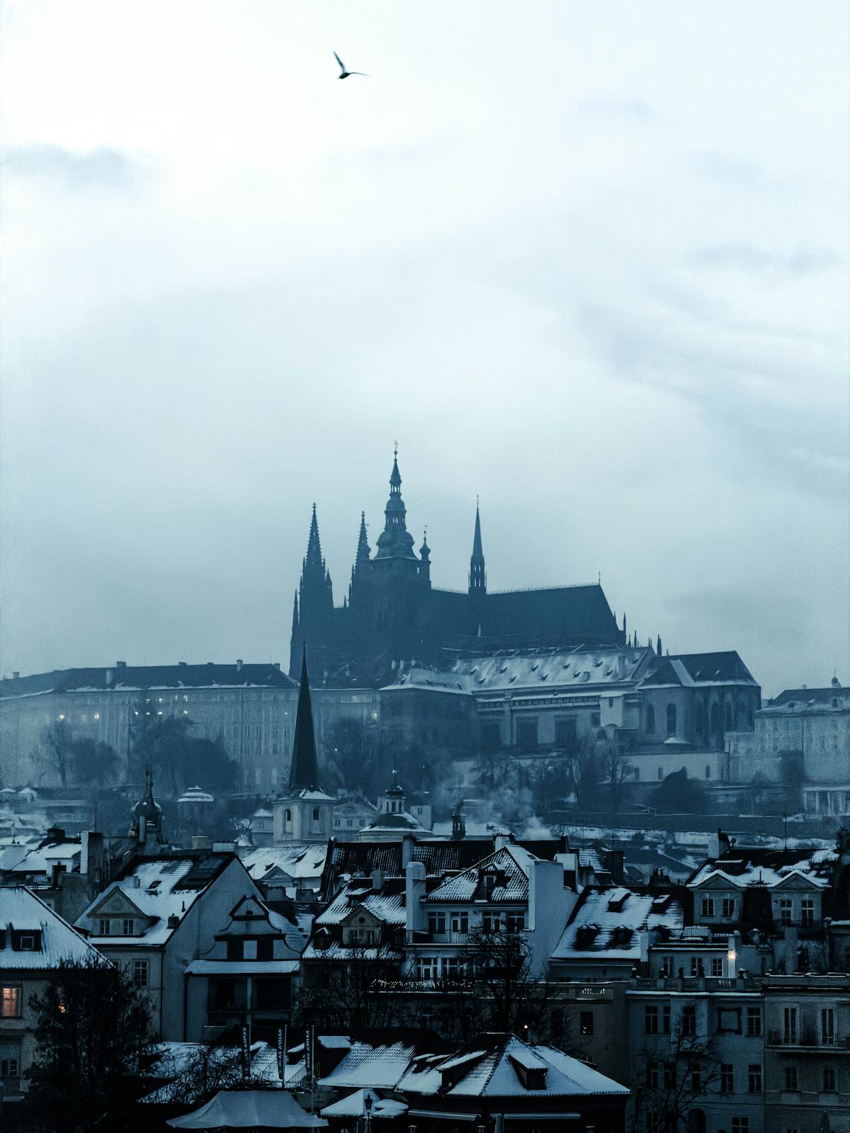 Scenic winter evening view of Prague Castle with snow-covered roofs