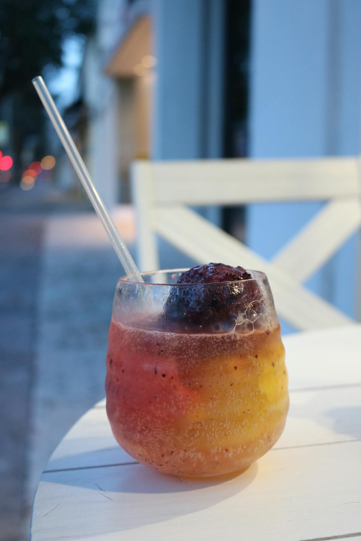 Chilled cocktail with fruit garnish on a patio table in evening light