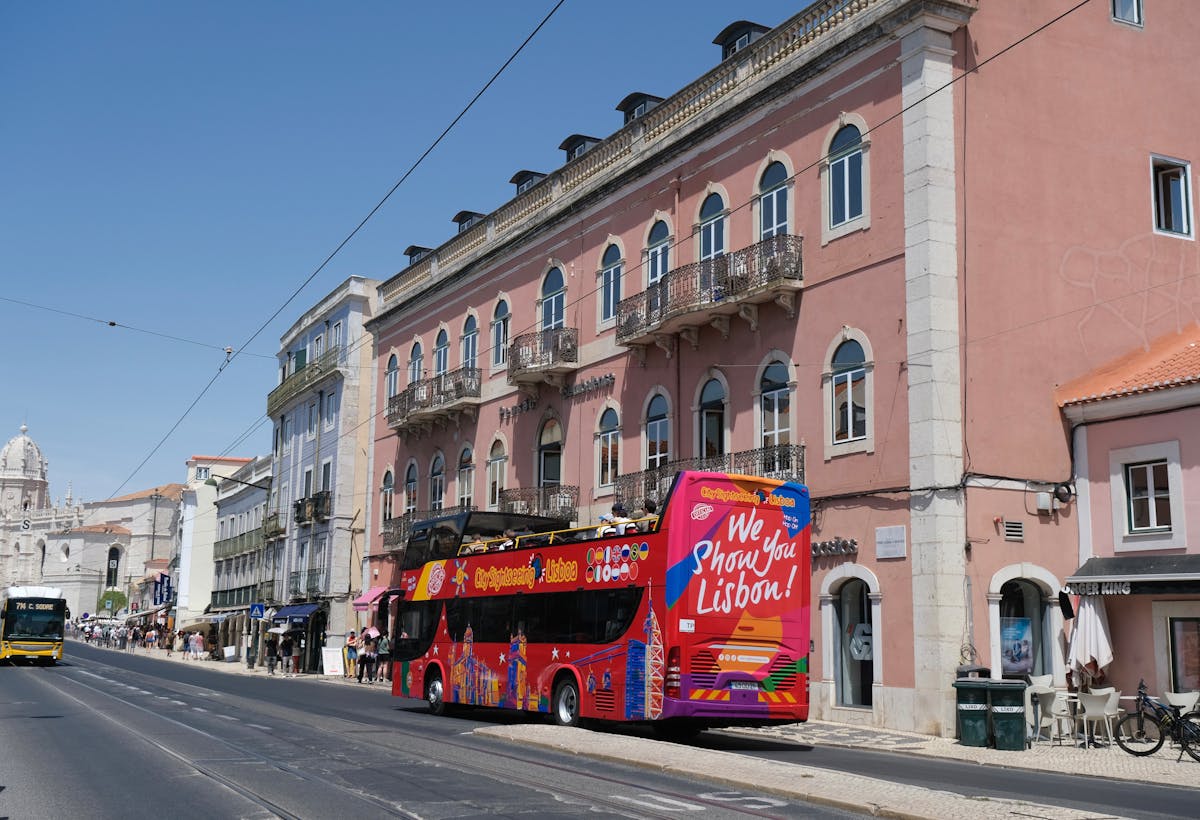 Historic yellow tram climbing a narrow Lisbon street lined with colorful buildings