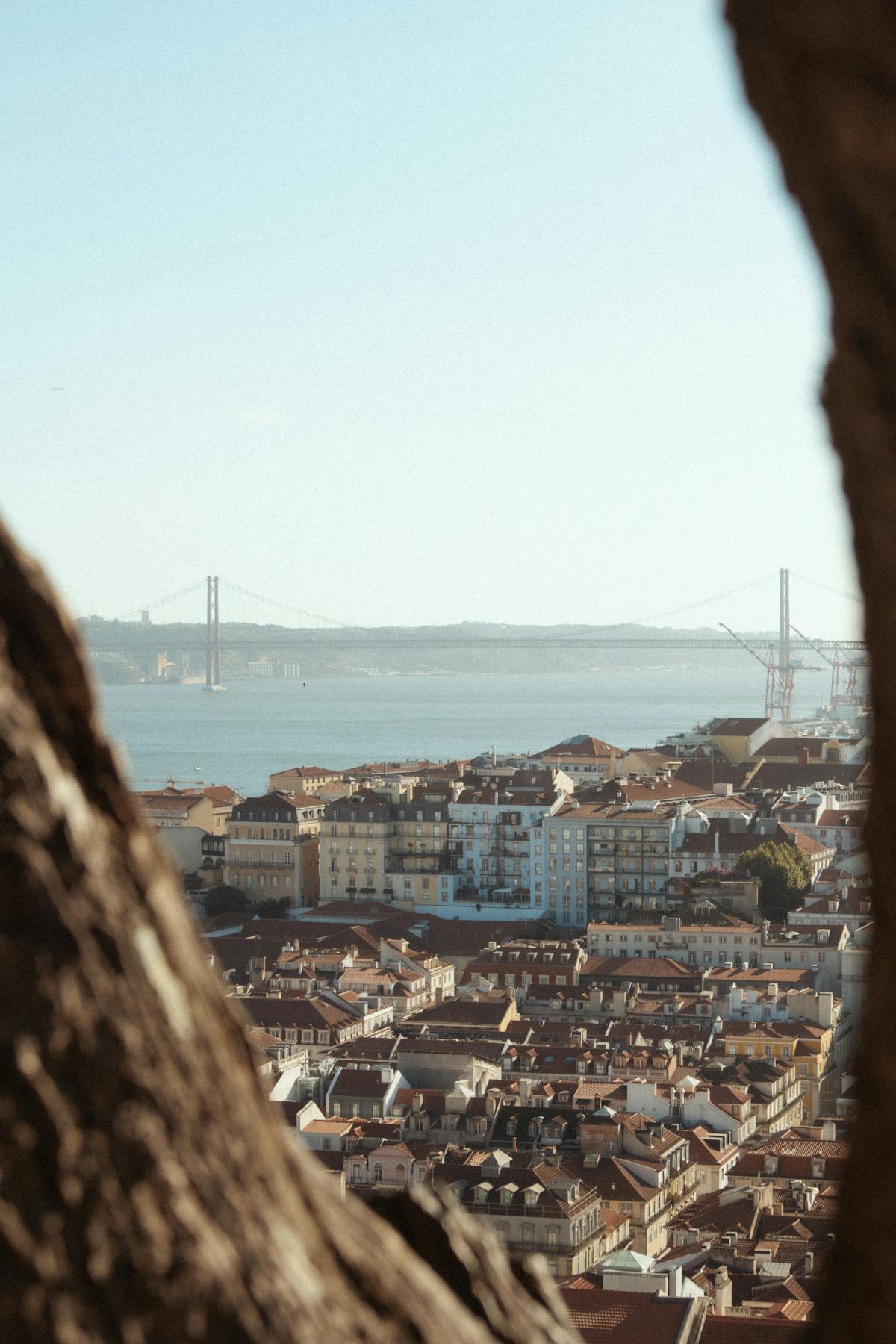 Colorful buildings cascading down a Lisbon hillside with river in background
