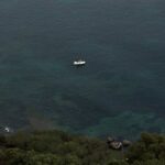 Aerial view of a yacht sailing near the Sardinian coast with turquoise Mediterranean water
