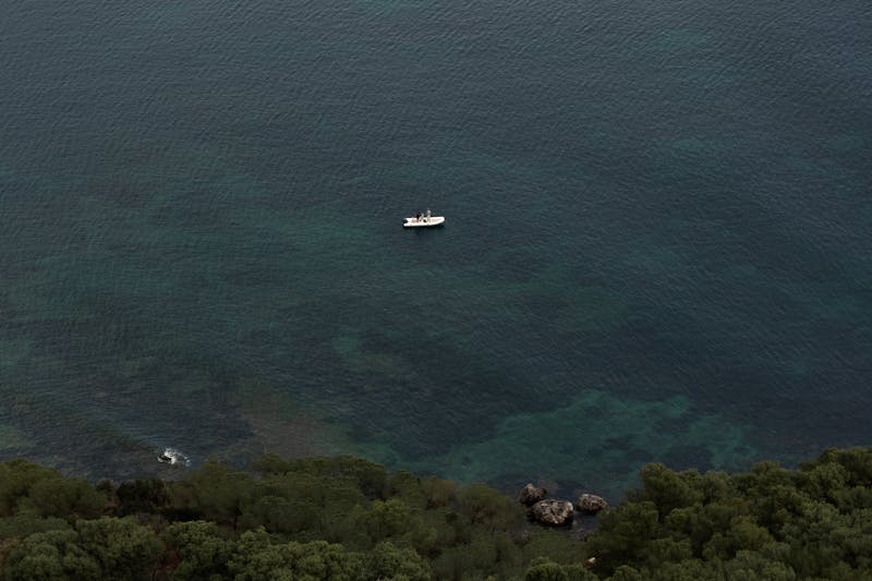 Aerial view of a yacht sailing near the Sardinian coast with turquoise Mediterranean water