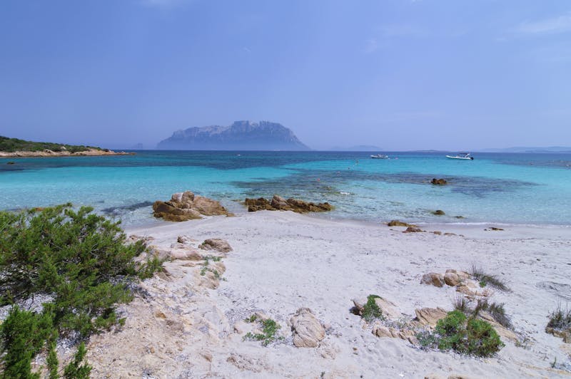 Sandy beach with turquoise waters and distant island view in Sardinia