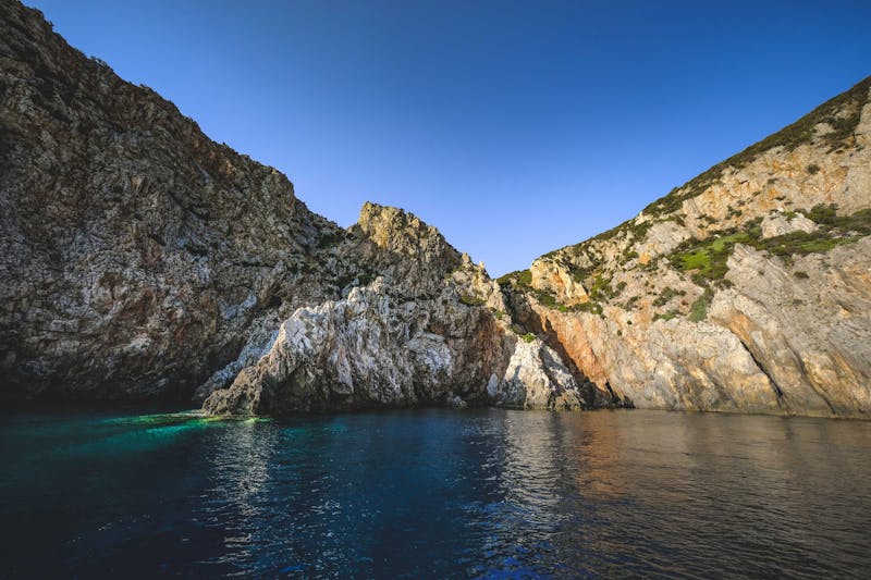 Colorful turquoise lagoon next to tall steep cliffs on the Sardinian coast