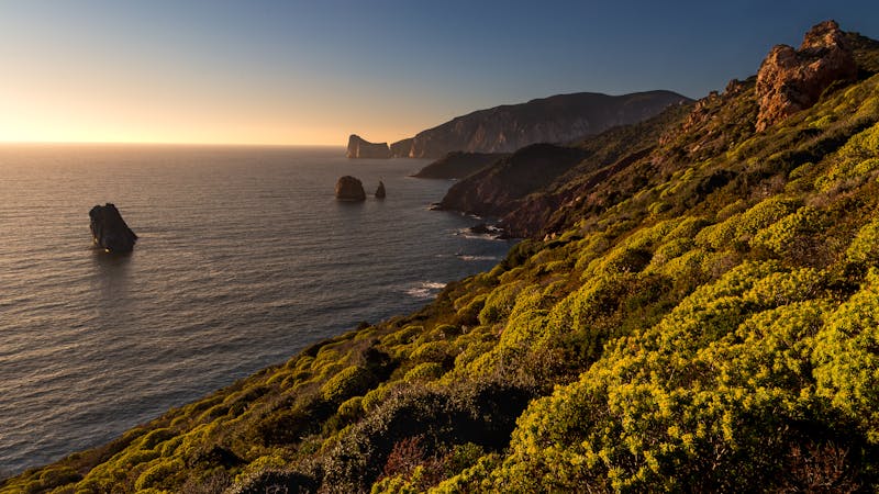 Rocky coastline of Sardinia during sunset with rugged cliffs and serene ocean