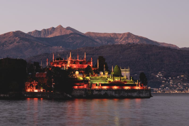 Isola Bella island silhouetted against a warm sunset with mountain backdrop on Lake Maggiore