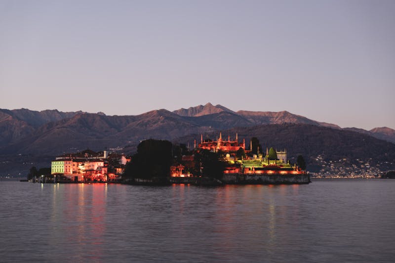 Isola Bella palace and gardens illuminated at twilight with mountain backdrop on Lake Maggiore