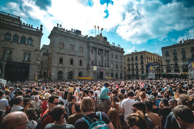 People gathered in a historic plaza in Barcelona with classic European architecture