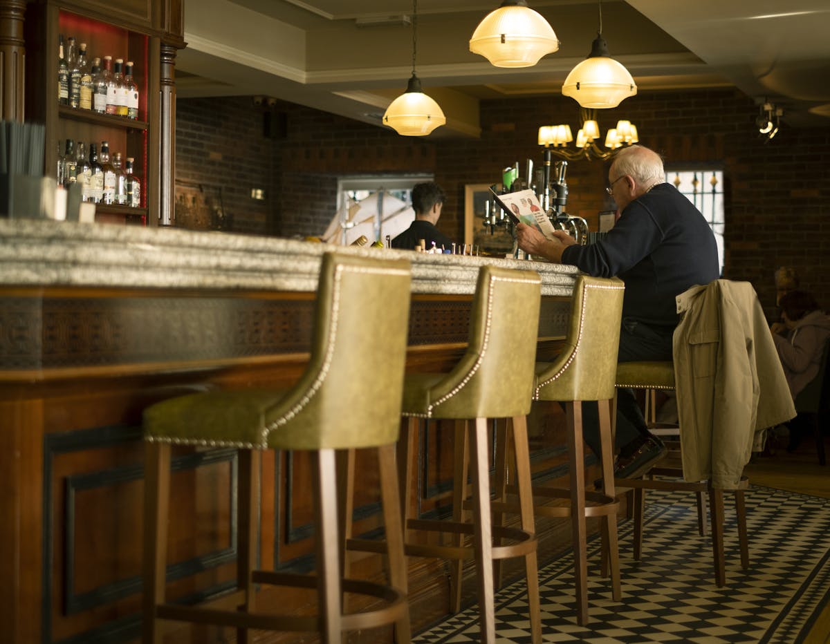 Man reading newspaper in a cozy Dublin pub with vintage decor