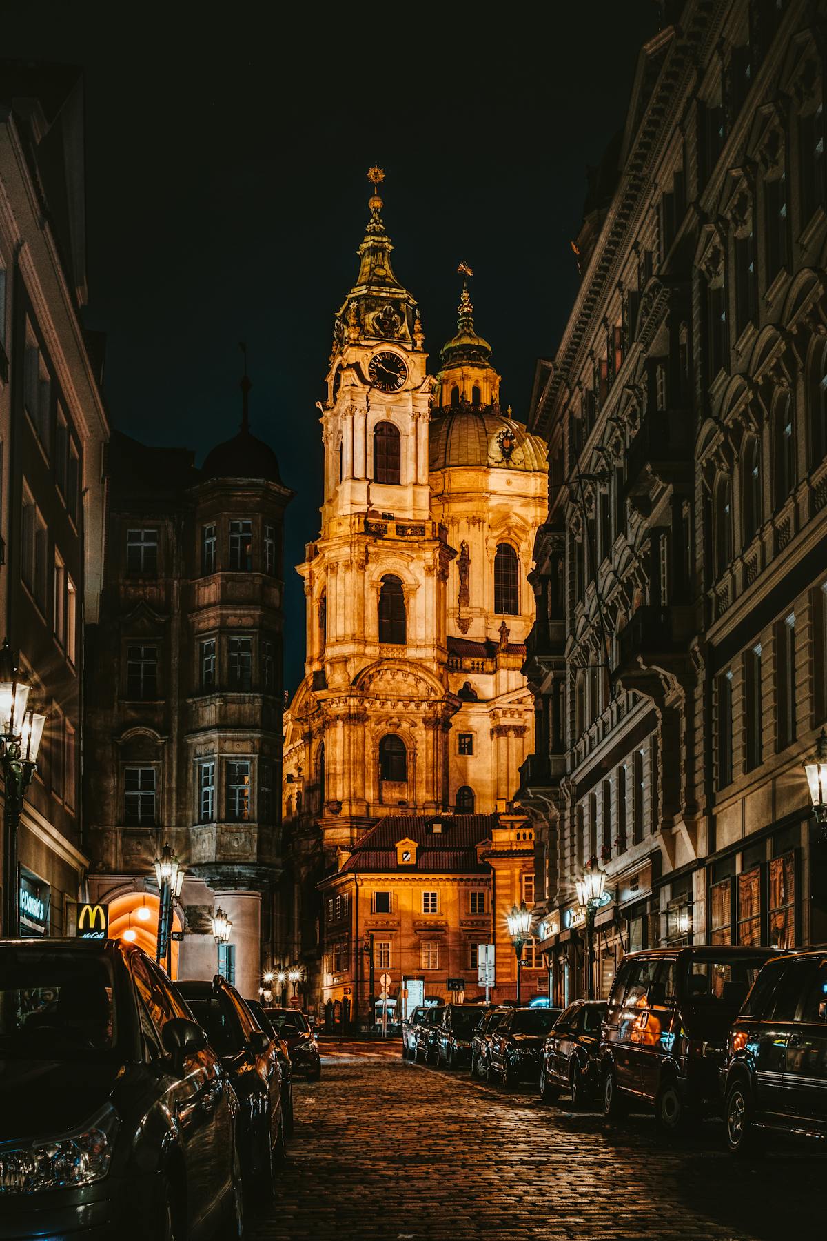 Prague street at night with a beautifully illuminated church in the background